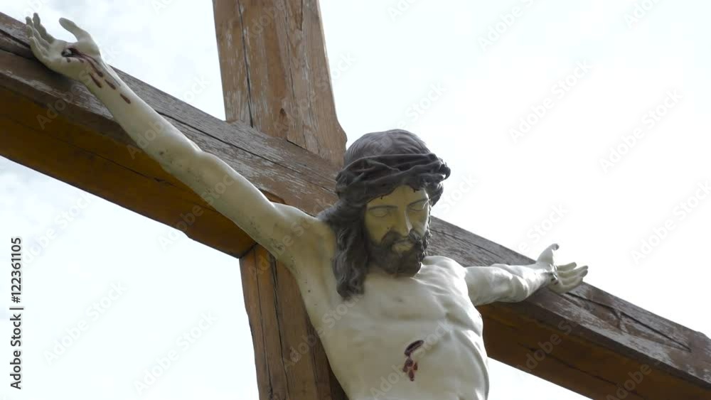 Jesus Christ crucified. The Crucifixion. Christian cross with Jesus Christ statue over stormy ...
