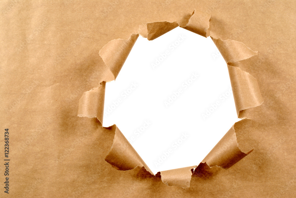Hole opening torn ripped in brown paper background looking through to ...