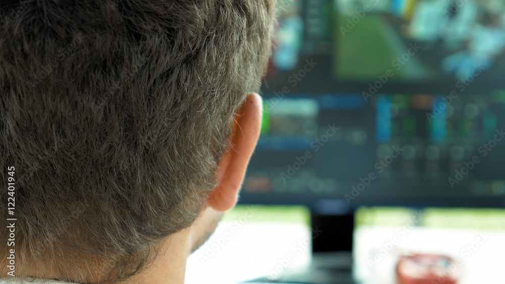 Video broadcast editor with headphones watching an action on the ...