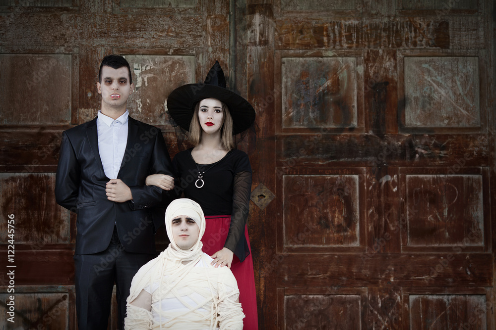 Vampire, Witch and Mummy are posing in front of the old rustic door of ...