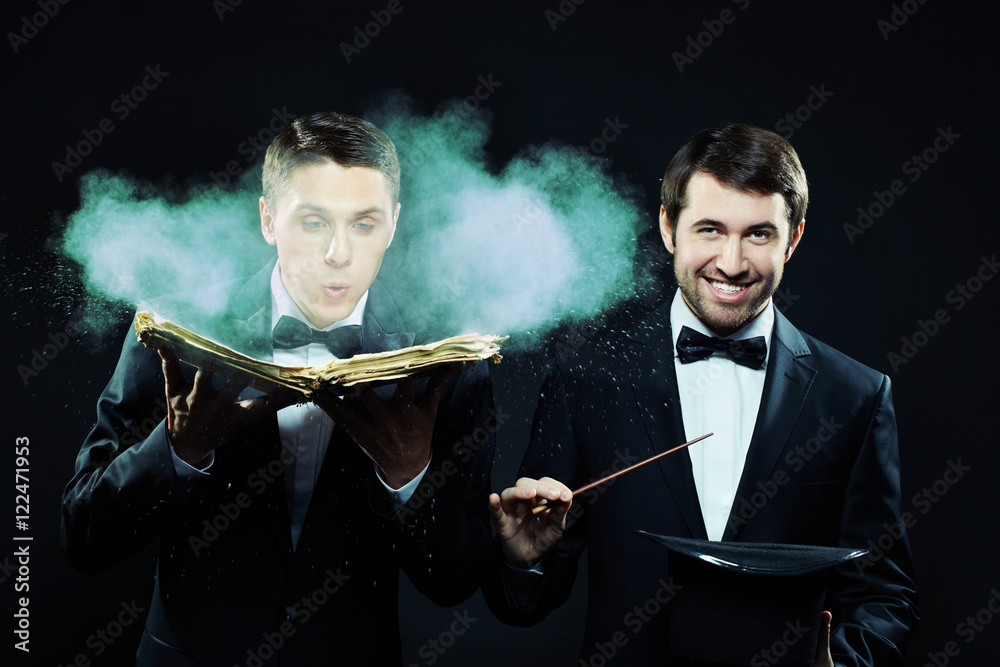 Portrait of two magicians with magic book and top hat ready to do their ...