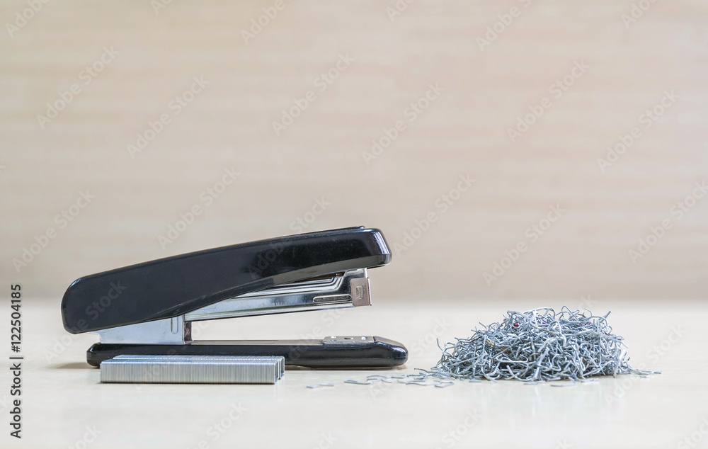 Closeup black stapler with blurred pile of used staples and new staples ...