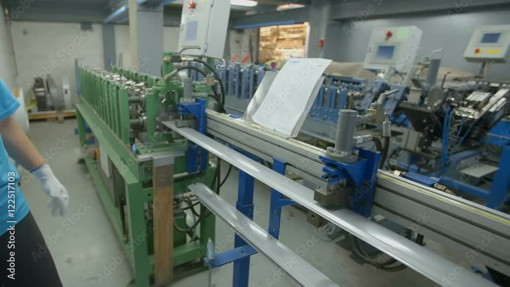 We can see a production of long thin metal pieces. A woman is waiting ...