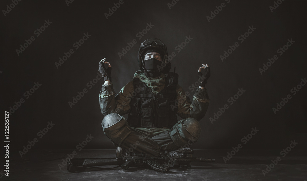 Young fitness member of special forces division meditation in dark room ...