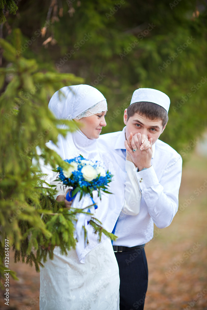 Muslim groom kisses the hand of a Muslim bride on the nature autumn day ...