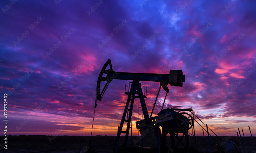Oil and gas well profiled on dramatic sunset sky, with wild colors, in ...