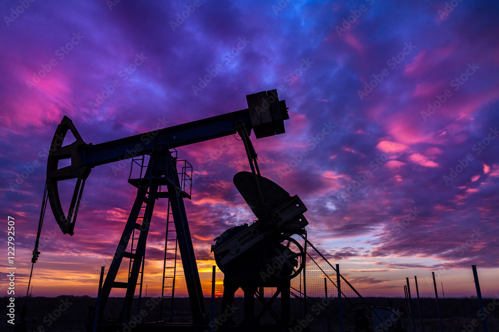 Oil and gas well profiled on dramatic sunset sky, with wild colors, in ...