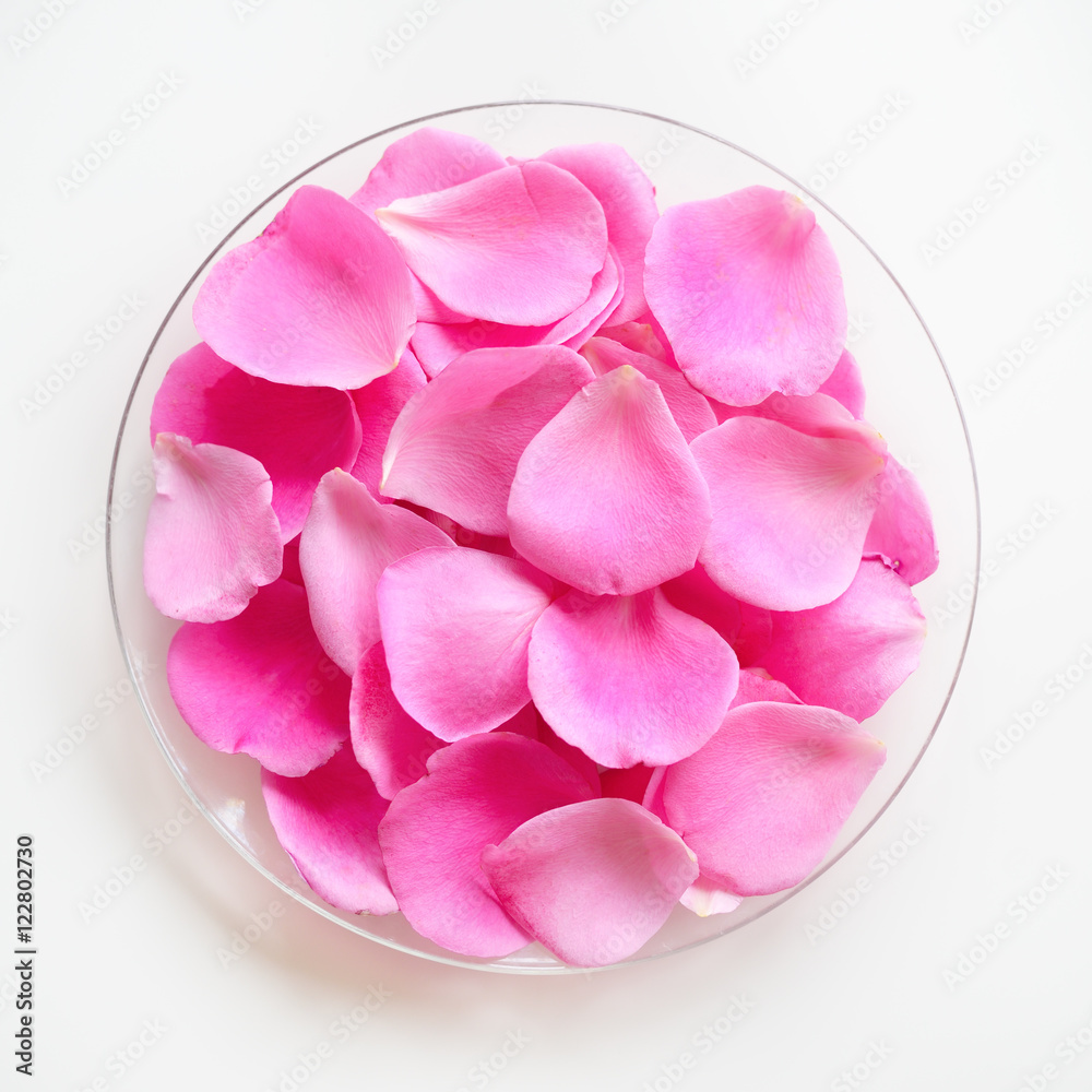 Many pink rose petals in glass bowl on a white background. Elegant ...