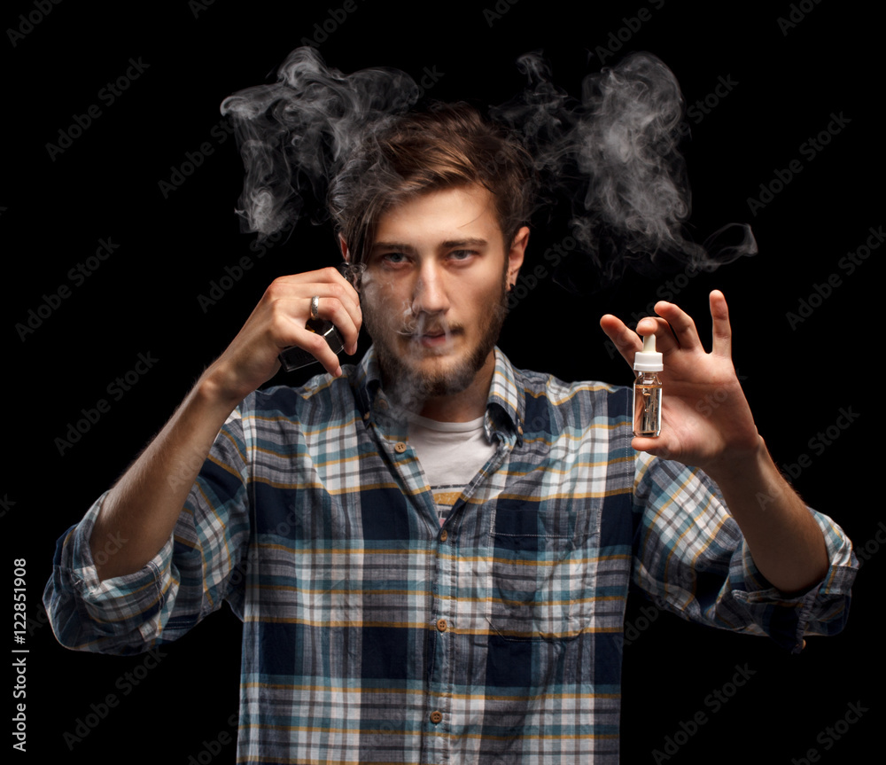 Man is vaping and holding e-liquid. Black background. Stock Photo ...