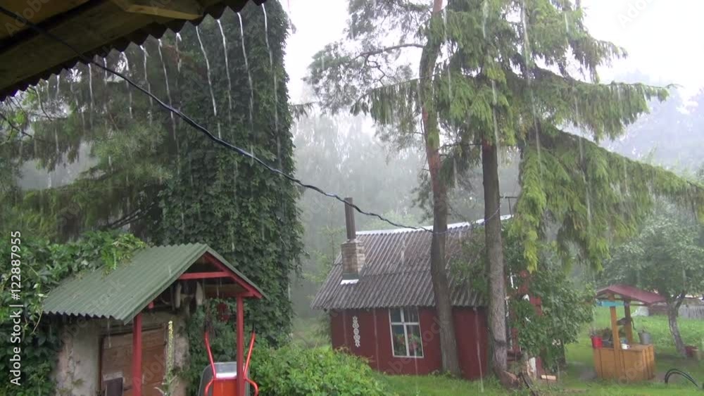 Rain falling on homestead and leaking off the roof on stormy summer day ...