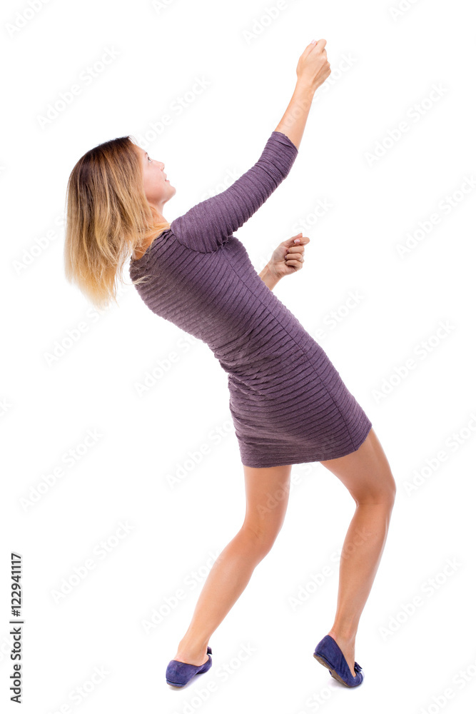 back view of standing girl pulling a rope from the top or cling to ...