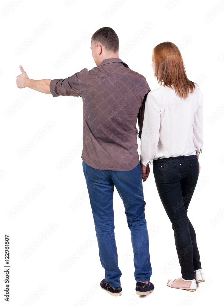 young couple pointing at wal Back view (woman and man). Rear view ...