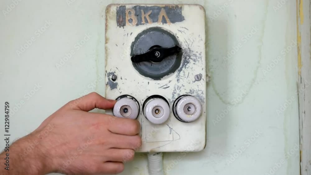 White man's hand to replace outdated ceramic fuse on an old scratched ...