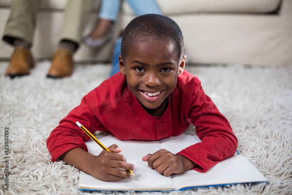 Boy doing homework while lying on the floor Stock Photo | Adobe Stock
