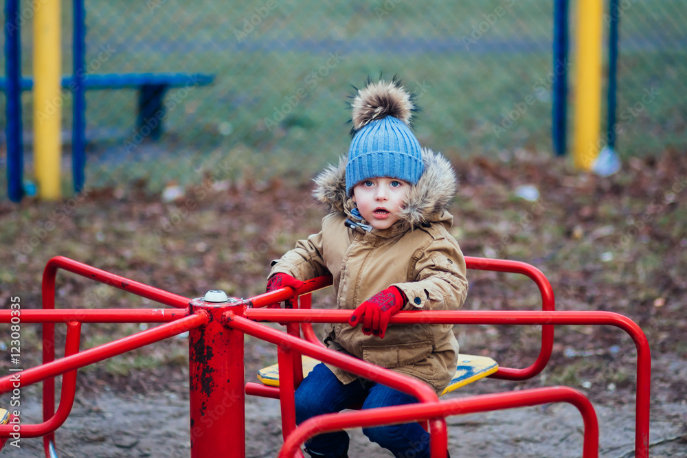 Cute little boy sitting on roundabout at playground Stock Photo | Adobe ...