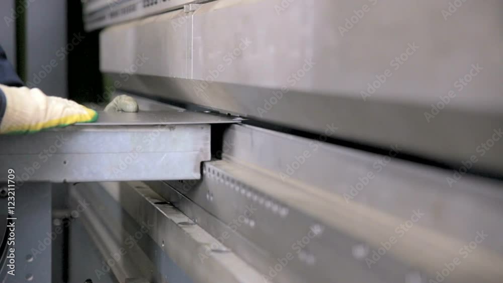 Worker hands bend metal sheet on a modern bending industrial machine at ...