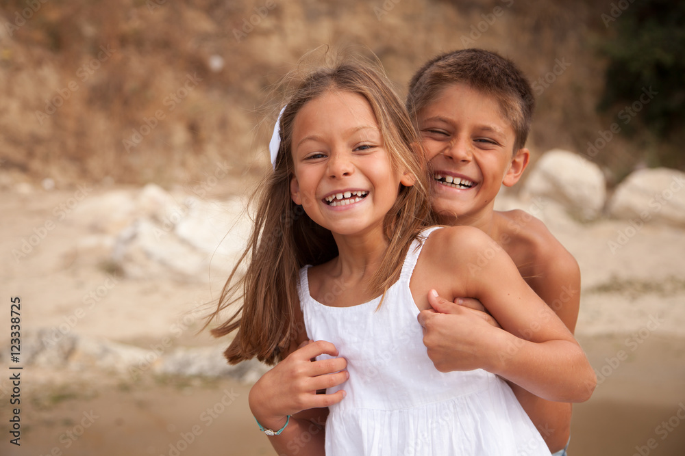 Portrait of a boy and girl on beach hugging and laughing Stock Photo ...