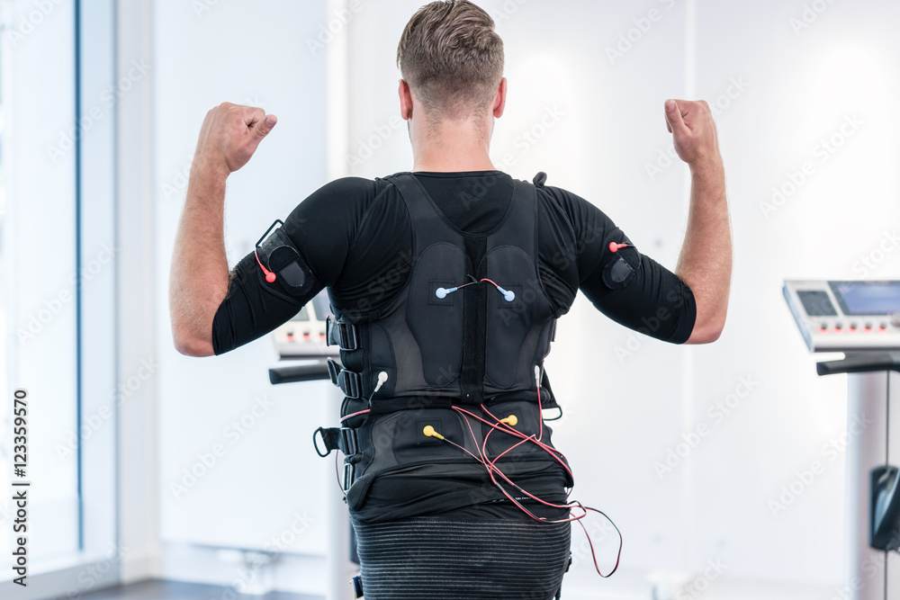 Man in EMS suit training his back in electro muscle stimulation gym ...