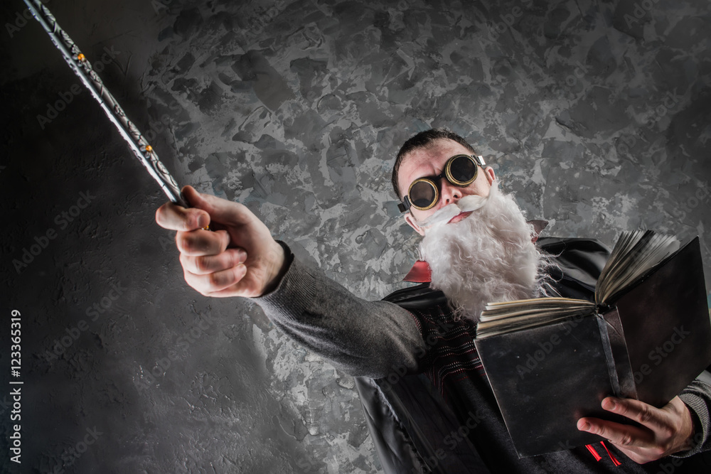 evil wizard Merlin conjures and casts a spell, raising his wand, a ...