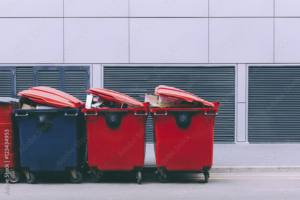 Red and blue garbage bins on roadside against wall Stock Photo | Adobe ...