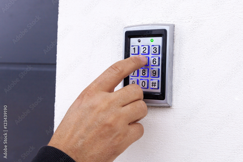 Man dialing pass code on intercom security keypad to open entrance door ...