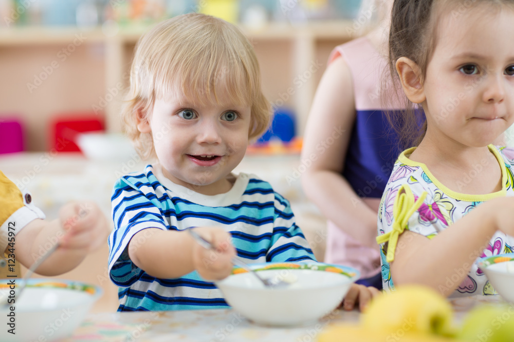 children eating from plates in day care centre Stock Photo | Adobe Stock
