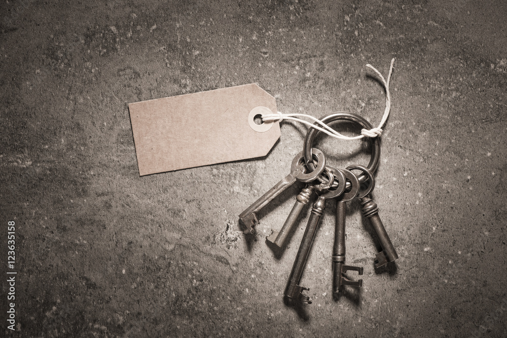 Vintage key set with blank paper tag on stone table. Symbol of ...