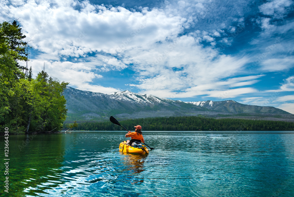 Kayaking in the spring by snow covered mountains on Lake McDonald in ...