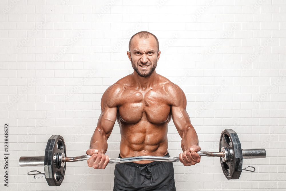 Studio portrait of handsome topless bodybuilder doing exercise on ...