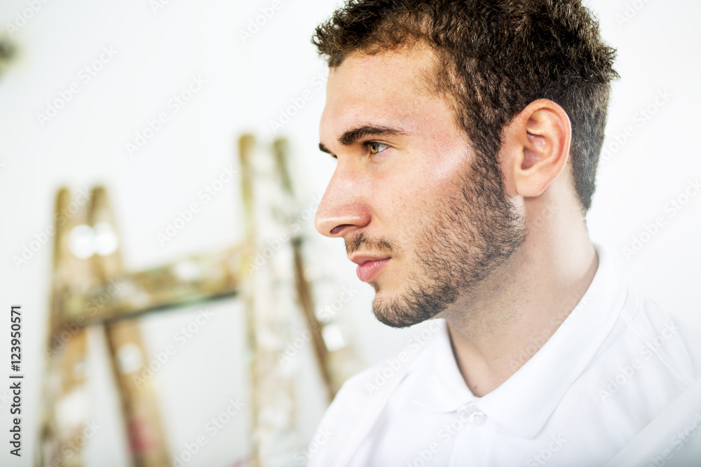 Portrait of young worker. Pretty young guy looking throw window. Close ...