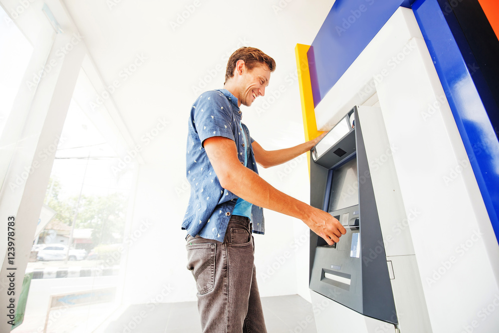 man using atm to withdraw cash Stock Photo | Adobe Stock