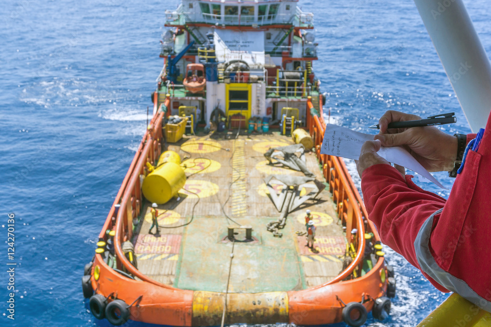 Offshore worker taking note while performing anchor handling operation ...