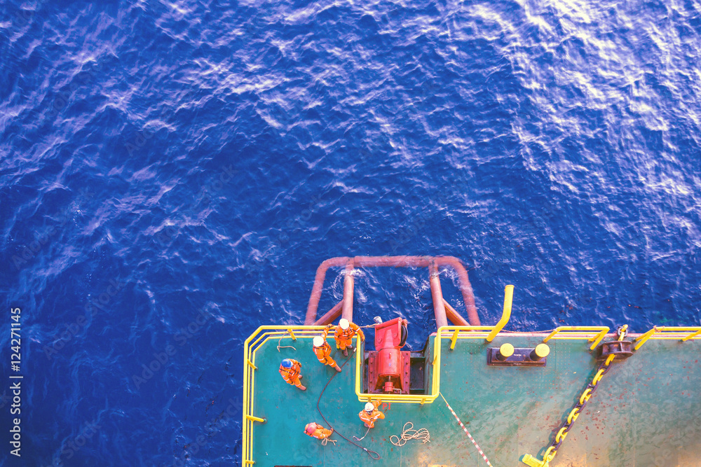 Offshore workers working together preparing the barge anchor fairlead ...