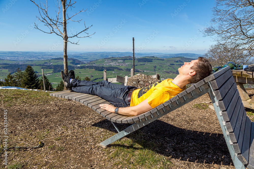 Young man lying on a wooden chair in the nature on the hill with Stock ...