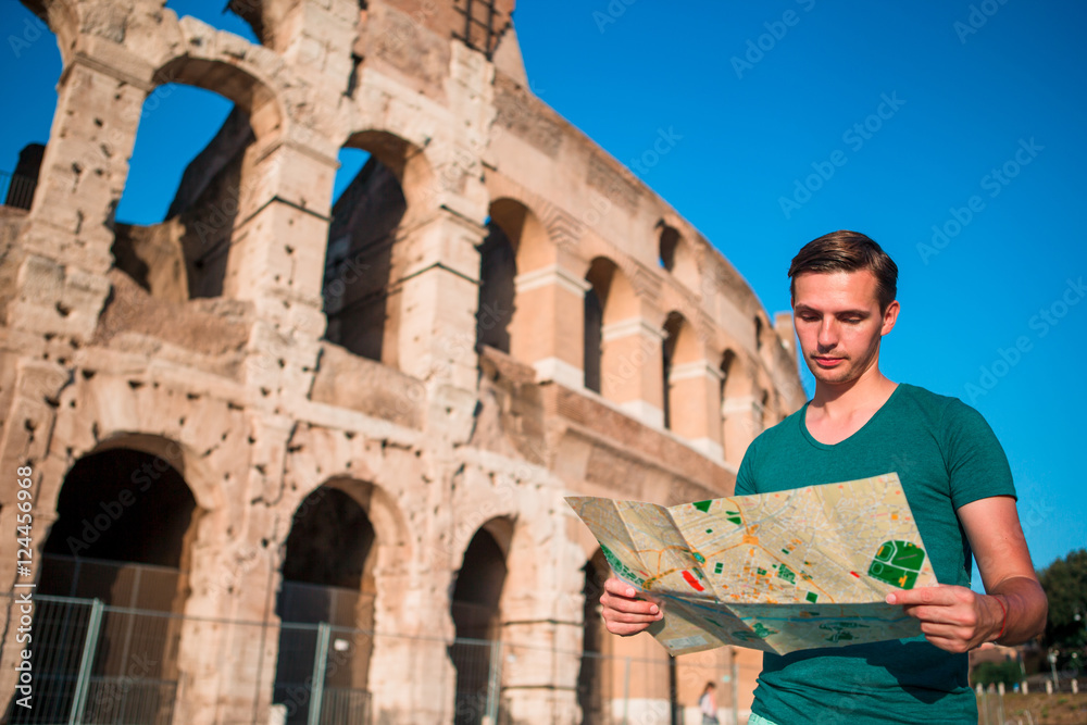 Boy with map in front of Colosseum. Young man searching the attraction ...