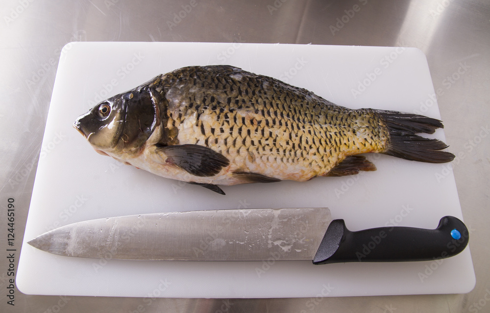 Cook cut up raw fish in kitchen Photos | Adobe Stock