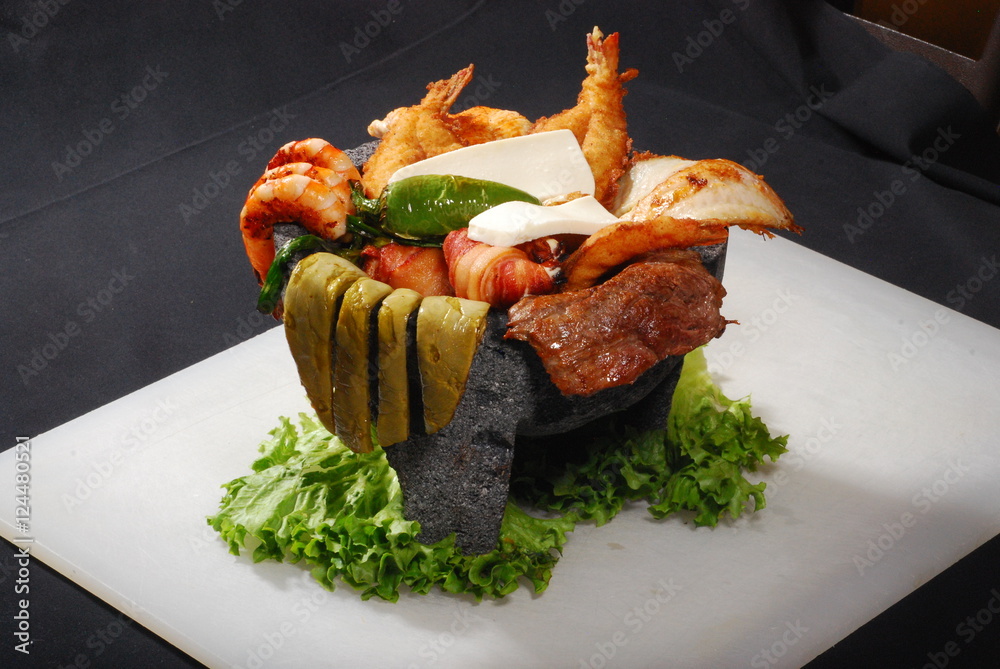 Molcajete azteca with shrimps, beef, fish, cactus and fresh cheese with ...