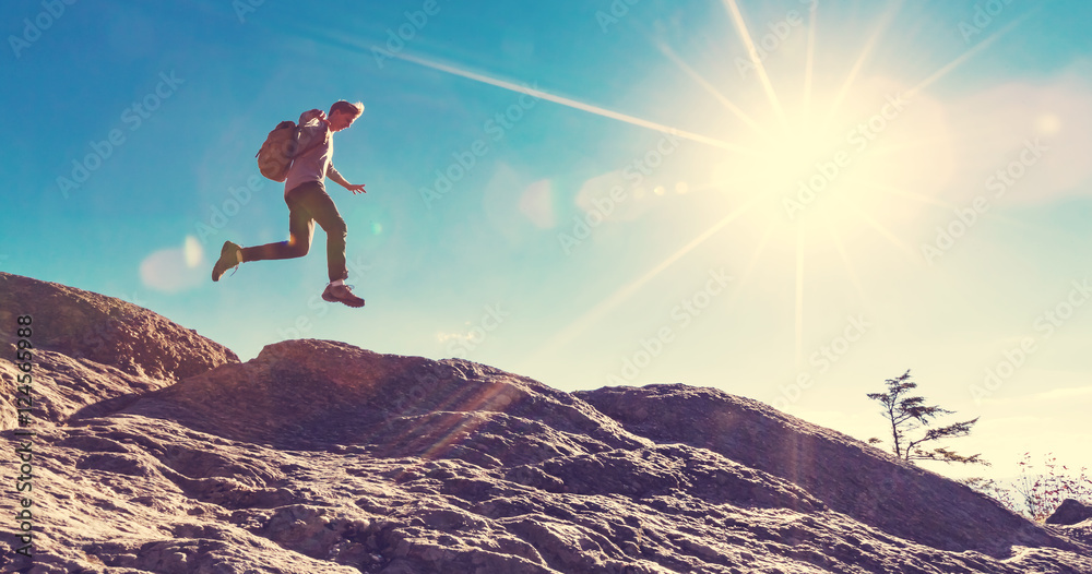 Man jumping over gap on mountain hike Stock Photo | Adobe Stock