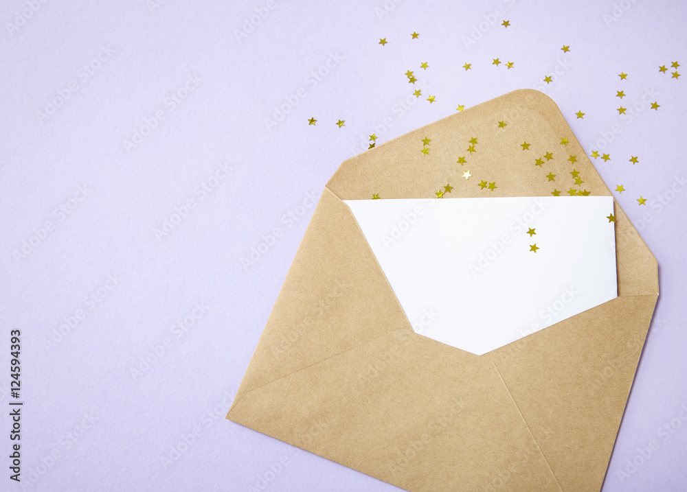 A brown envelope with letter and gold sequin stars spilling out on to a ...