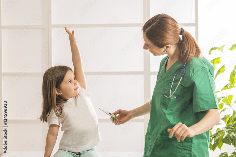 Doctor checking little girl's temperature with digital thermometer ...