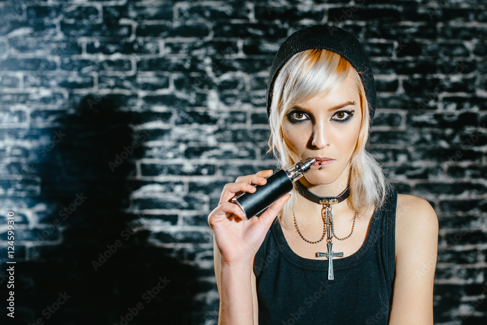 Sexy goth girl smokes electronic cigarette on dark background. The ...