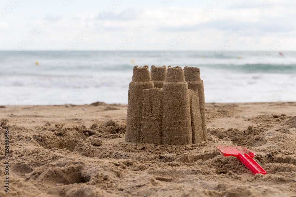 Kinder bauten eine schöne Sandburg am Strand, mit Meer im Hintergrund ...