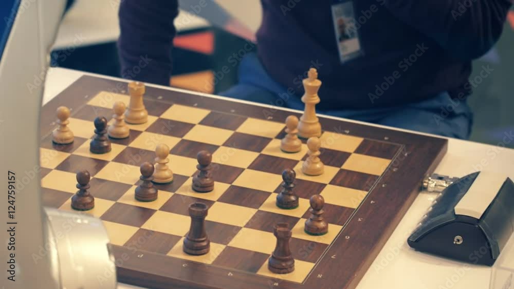 Robot playing chess with a man. Hand manipulator moves the chess and ...