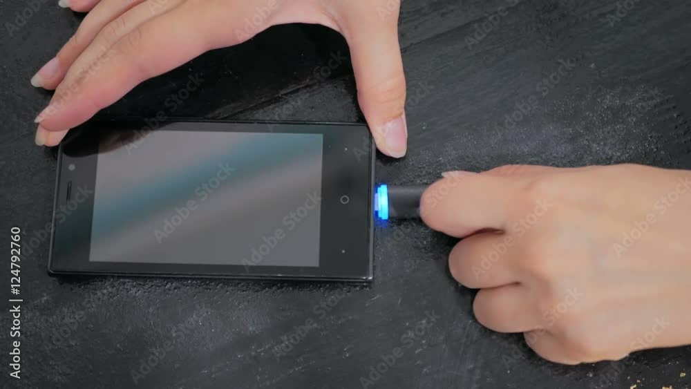 Woman's hand plugging black lightning charging cable into smartphone ...