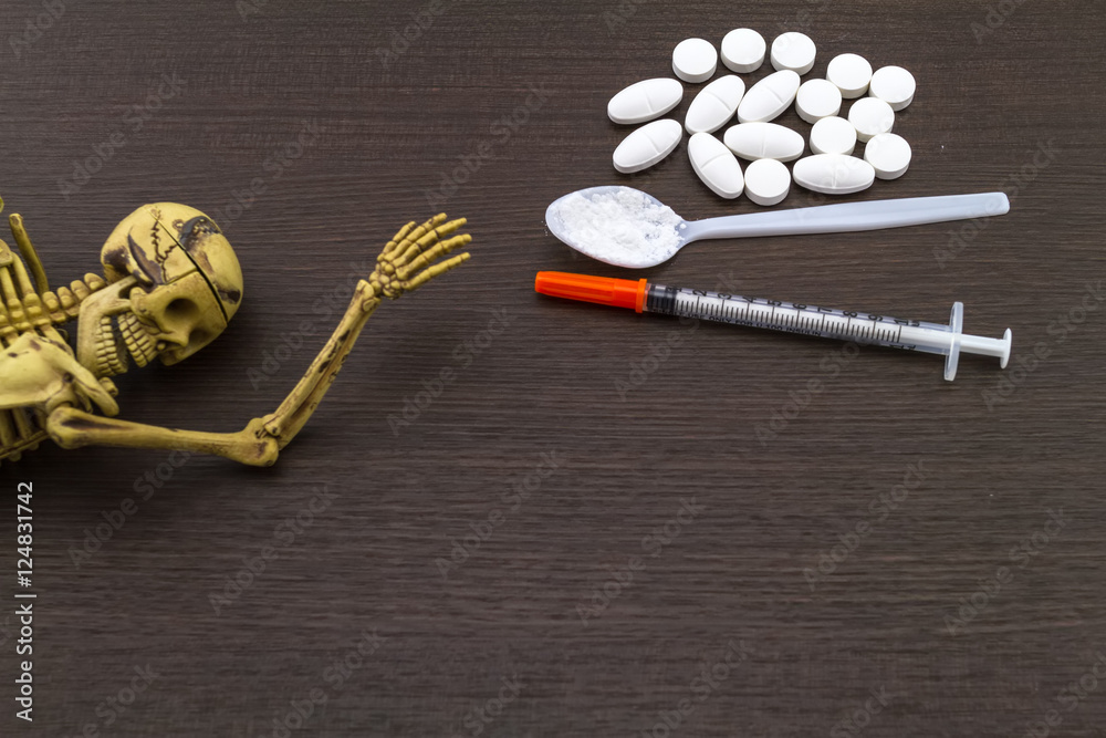 Skull and drugs with insulin syringe. Next to them are a spoon with ...