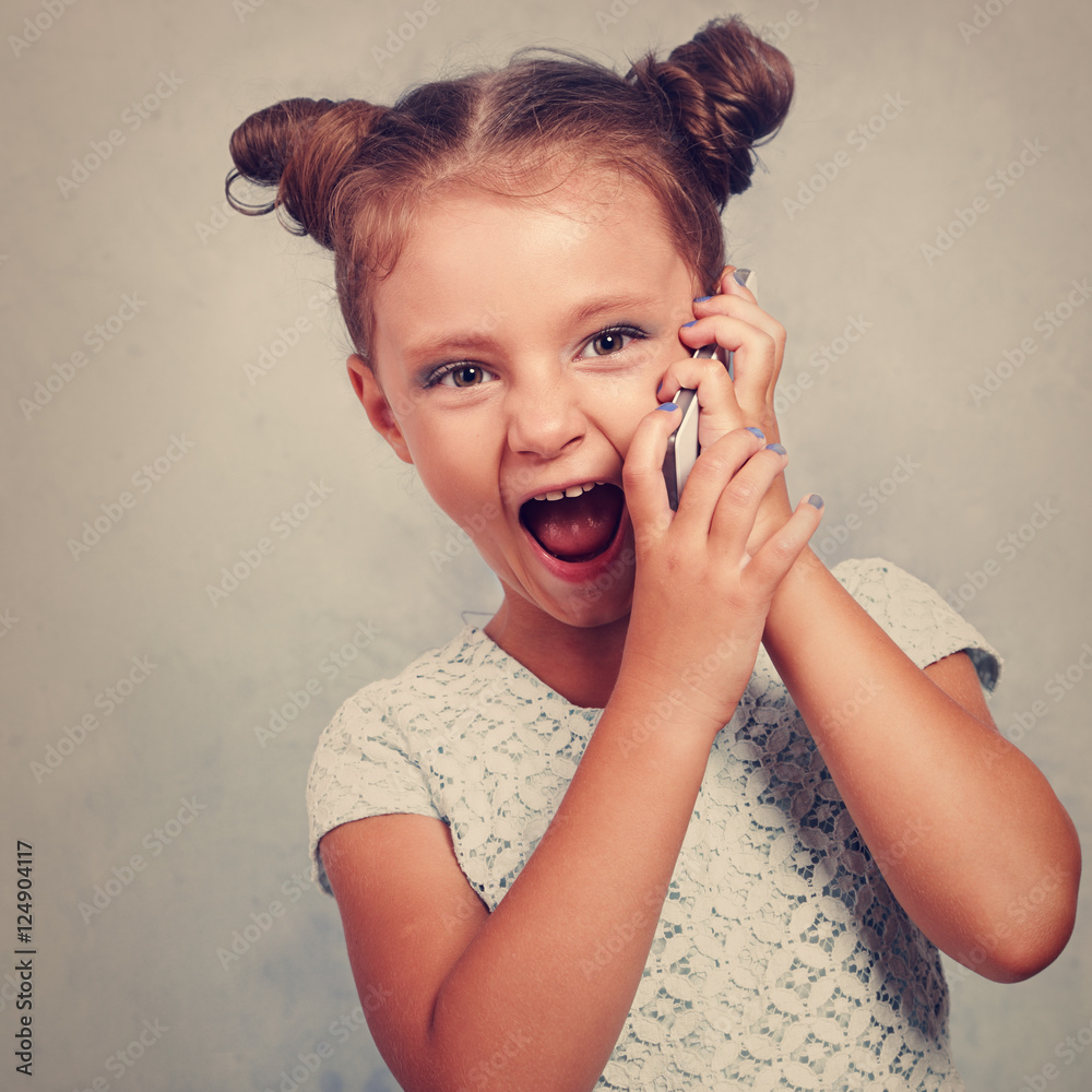 Excited kid girl talking on mobile phone with opened mouth on bl Stock ...