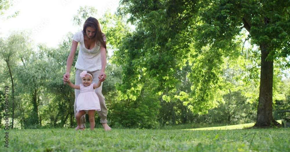 On a sunny day a baby takes its first steps on its own and in the hands ...