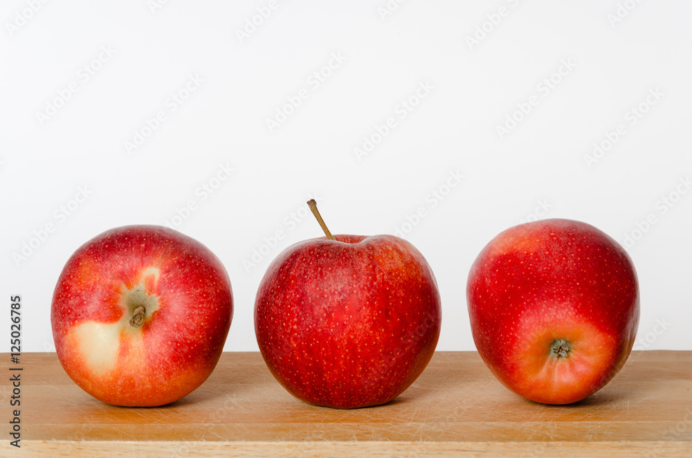 Front, rear and side look of tree apples in line on a chopping board ...
