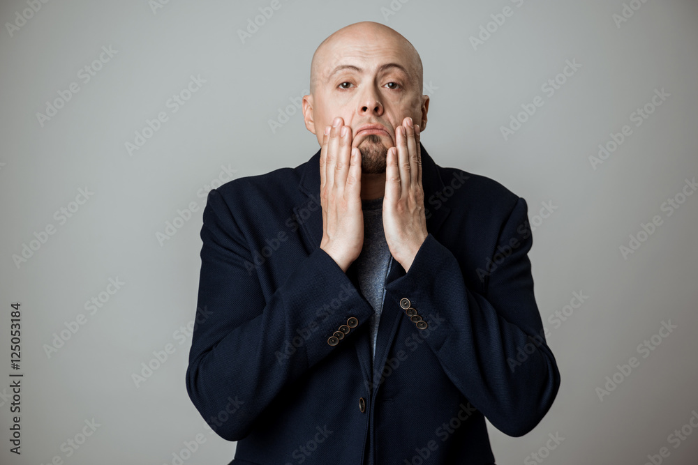 Young upset businessman grab his face over beige background. Stock ...