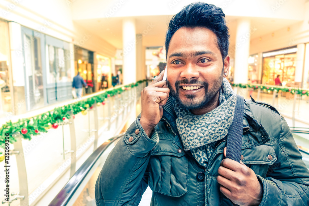 Young happy indian man making phone call smiling and wearing winter ...